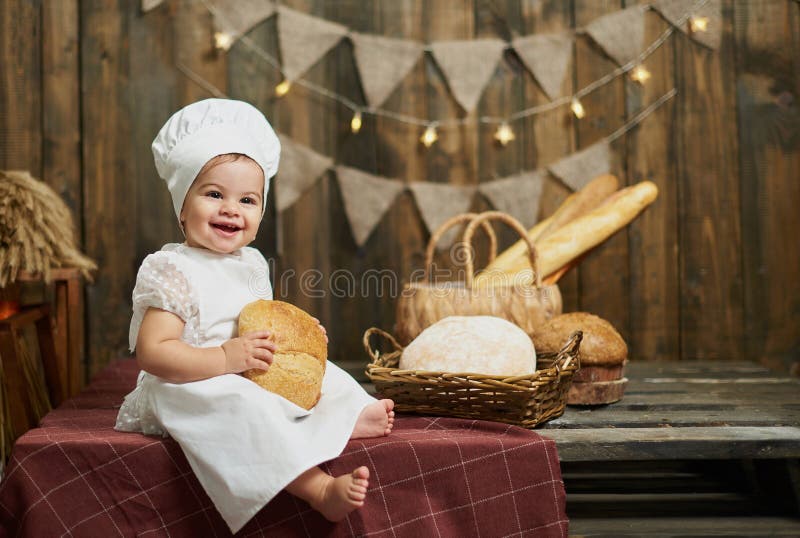 Little Baby Baker Holding Bread and Wide Smiling in a Rustic Interior ...