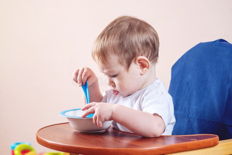 Little Baby Boy Learning To Eat at the Kid Table Studying a Plate and ...