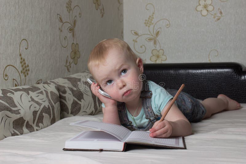 Little Baby Lying on the Couch and Writing in a Notebook Pen Stock ...