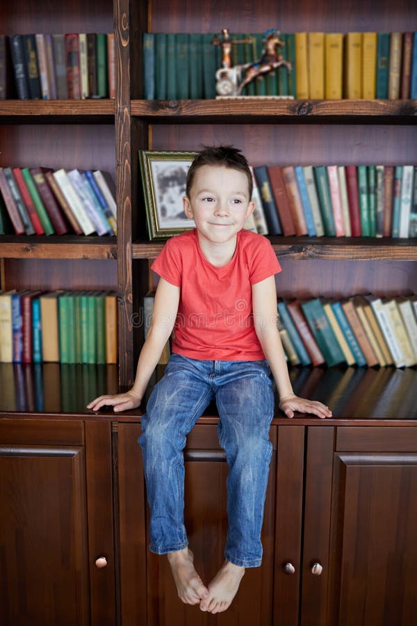 Little Barefoot Boy Sits on Bookcase with Stock Image - Image of happy ...