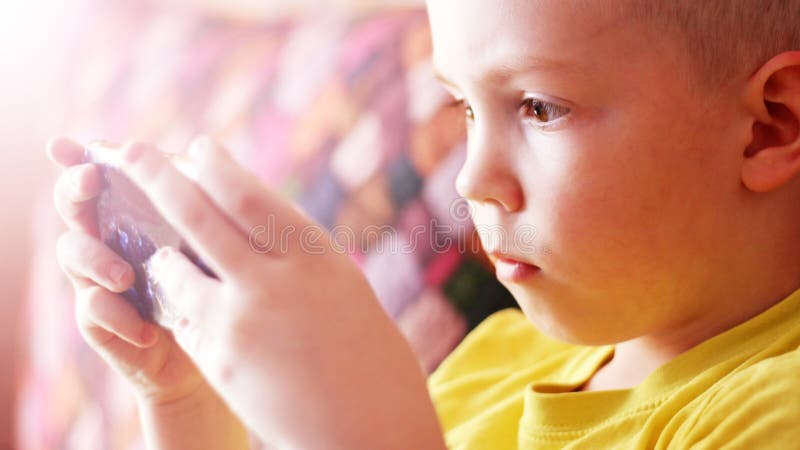 Little Blond Boy is Watching Something on a Smartphone Stock Image ...