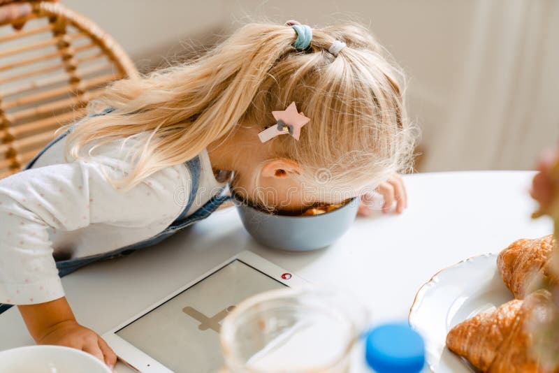 Little Girl Having Breakfast and Using Tablet Computer at Home Stock ...