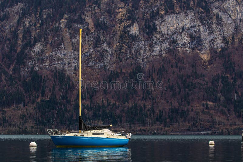 Little Blue Boat Sat on Swiss Lake by a Forest and Mountain Side Stock ...