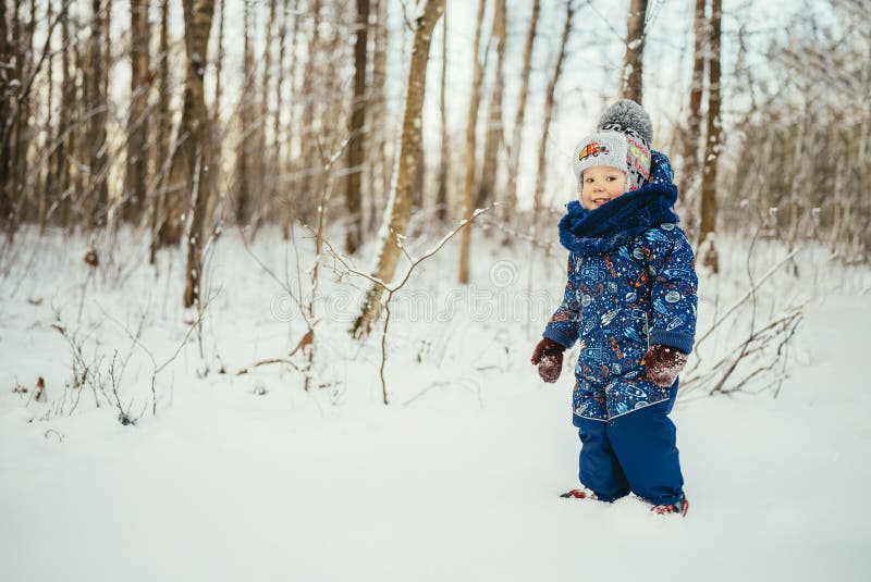 A Little Boy in a Blue Jacket in a Snowy Forest Smiles on a Cold Day ...