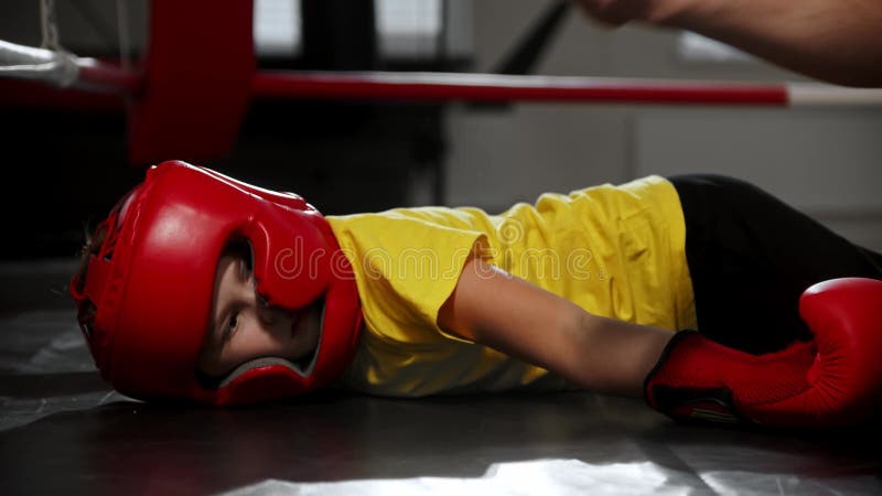 Little Boy in Boxing Gloves and Soft Helmet Falls Down on the Ring in ...