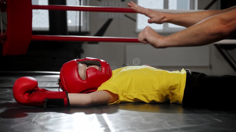 Little Boy in Boxing Gloves and Soft Helmet Lying Down on the Ring and ...
