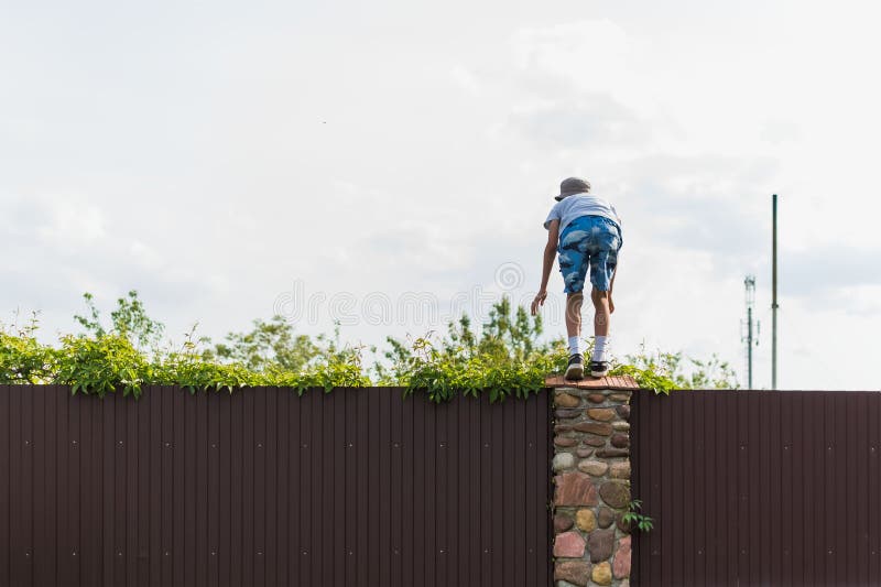 A Little Boy Climbs Over a Fence on a Private Plot Stock Image - Image ...