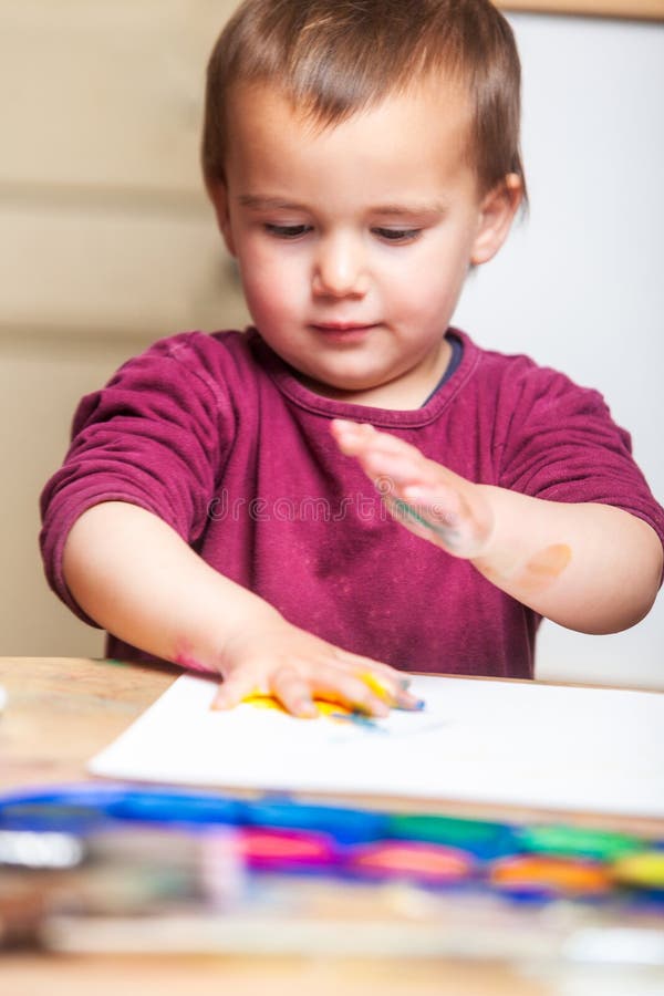 A Little Boy Creates a Work of Art on a Piece of Paper with the Paint ...