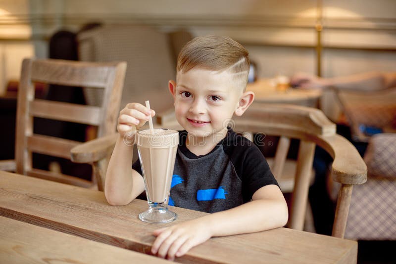 Little Boy Drinking Milkshake Sitting at the Table in Cafe Stock Photo ...