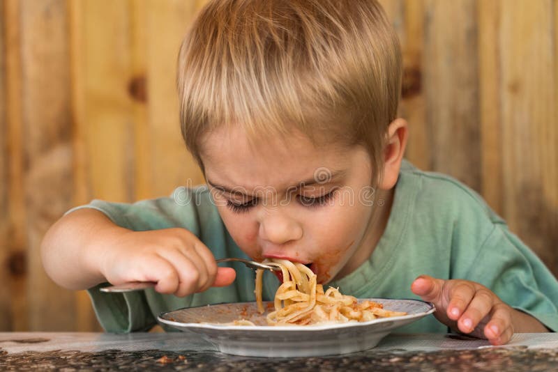 A Little Boy Eagerly Eats Spaghetti with Ketchup and Parmesan Stock ...