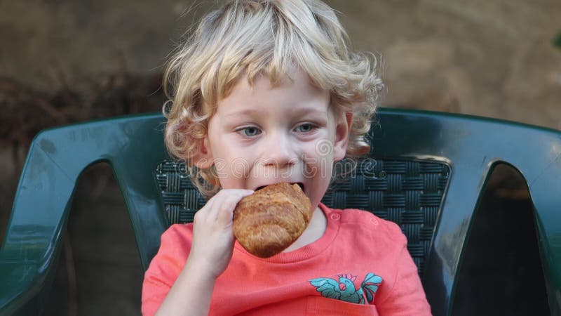 A Little Boy is Eating Pastry in the Garden Stock Footage - Video of ...