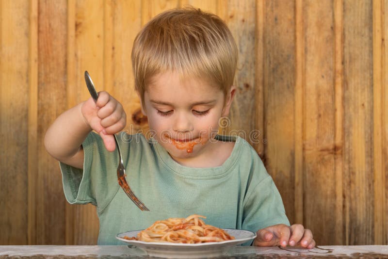 A Little Boy is Eating Spaghetti. His Face is Smeared with Ketchup ...
