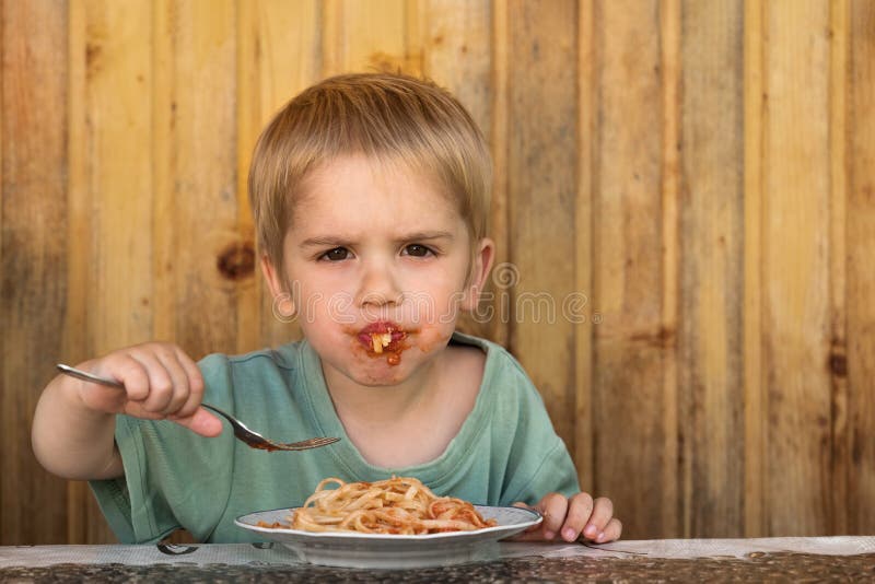 A Little Boy is Eating Spaghetti. His Face is Smeared with Ketchup ...