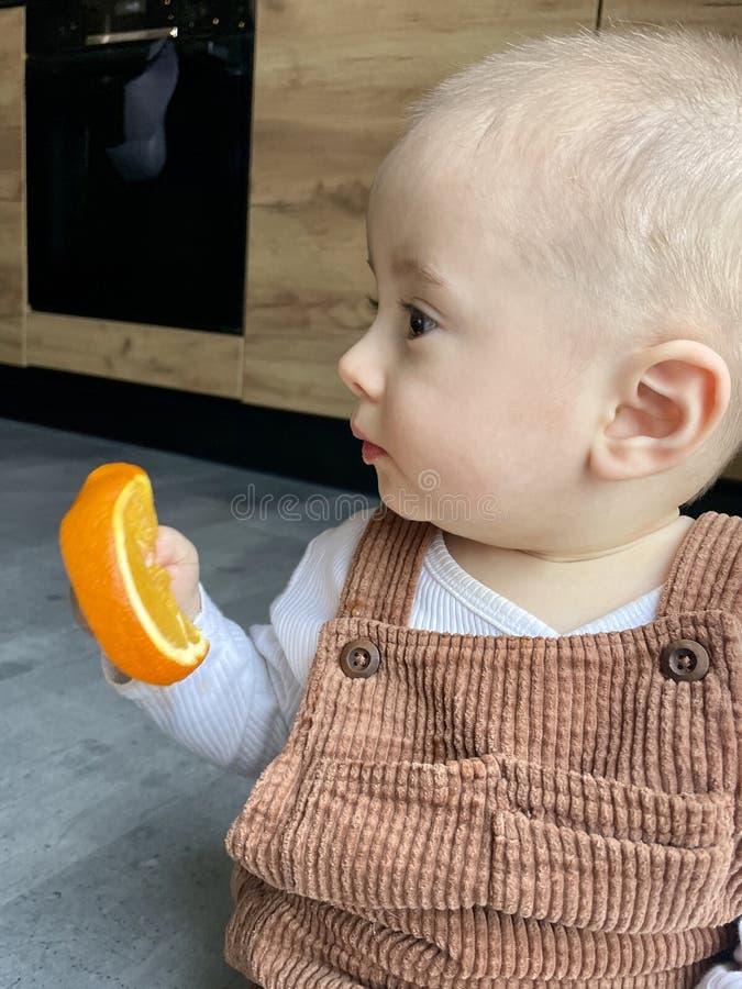 A Little Boy Eats a Piece of Orange by Himself Stock Image - Image of ...
