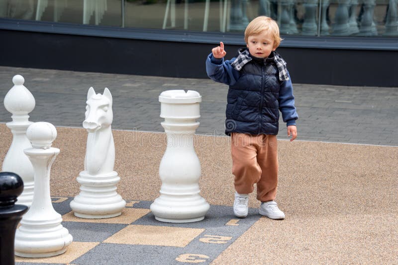 Little Boy Exploring a Life-sized Chess Board Outdoors, Interacting ...