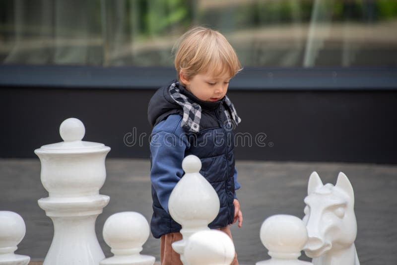 Little Boy Exploring a Life-sized Chess Board Outdoors, Interacting ...