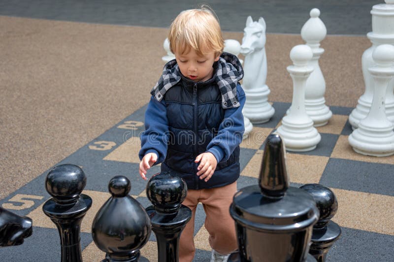 Little Boy Exploring a Life-sized Chess Board Outdoors, Interacting ...