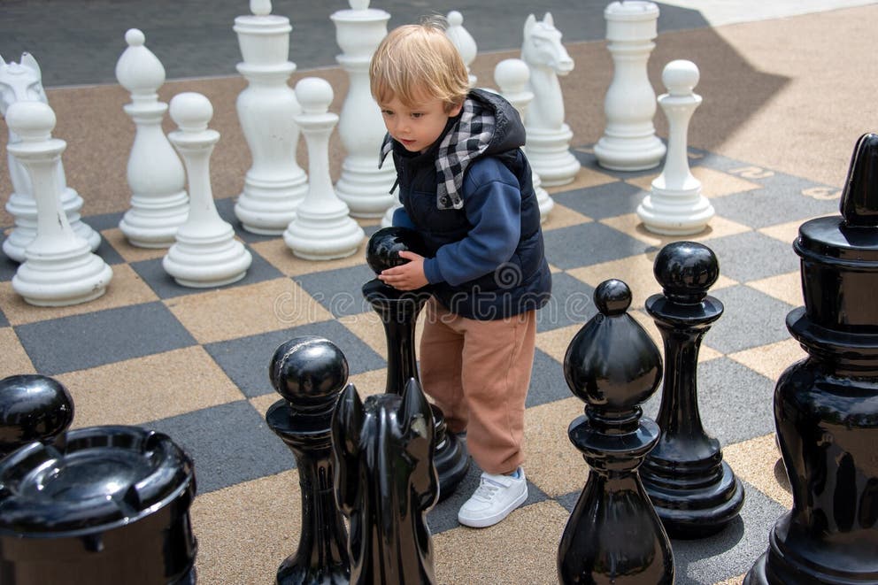 Little Boy Exploring a Life-sized Chess Board Outdoors, Interacting ...