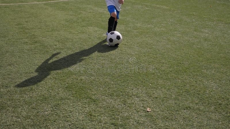 A Little Boy is Playing Soccer on the Football Field, he Hits the Ball ...