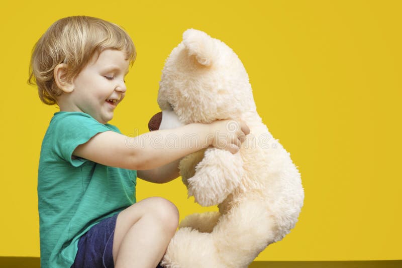Little Boy Hugging Teddy Bear Toy on Yellow Background Stock Image ...