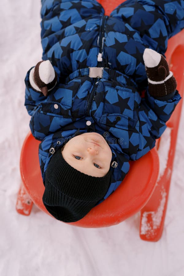 Little Boy in a Jacket and Hat Lies on a Sleigh. Top View Stock Image ...