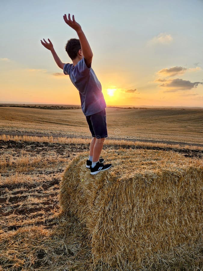 Little Boy Jumping on a Haystack at Sunset in the Countryside. Stock ...