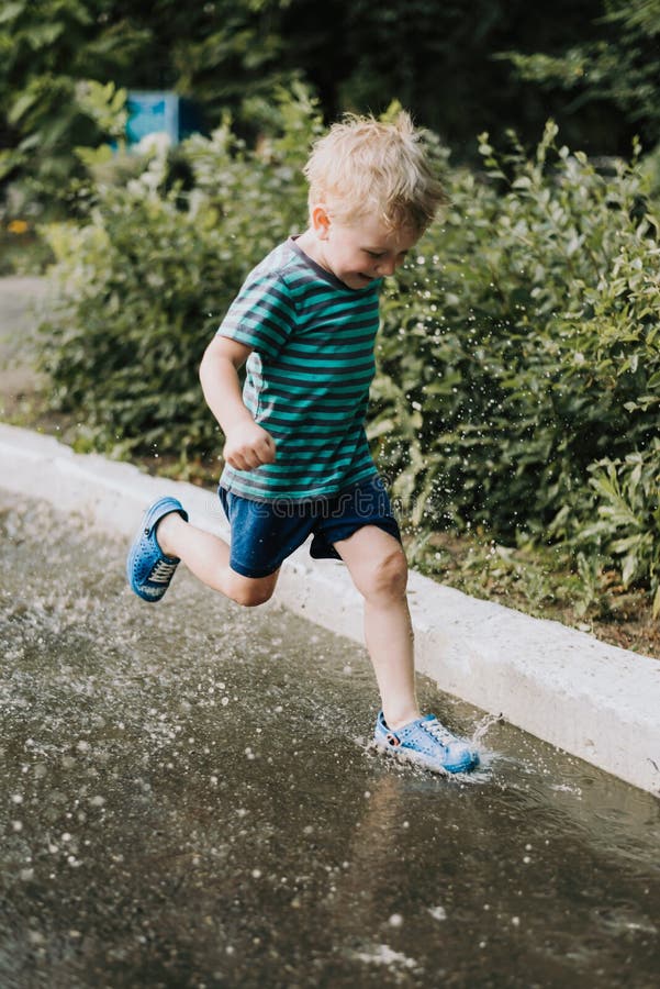 Little Boy Jumping in a Puddle in Summer Stock Photo - Image of rain ...