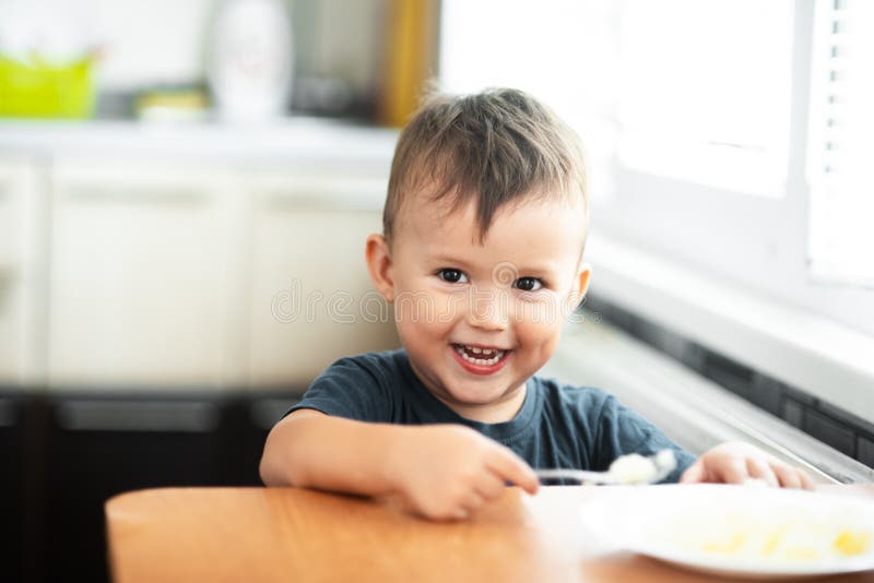 A Little Boy in the Kitchen Greedily Eats Rice with a Spoon Stock Photo ...