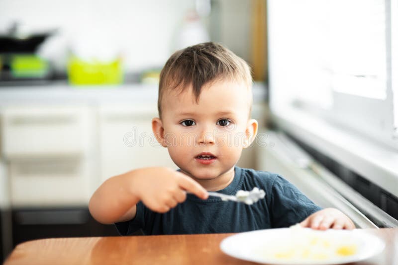 A Little Boy in the Kitchen Greedily Eats Rice with a Spoon Stock Image ...