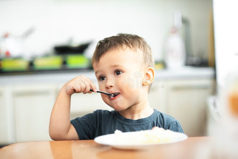 A Little Boy in the Kitchen Greedily Eats Rice with a Spoon Stock Image ...