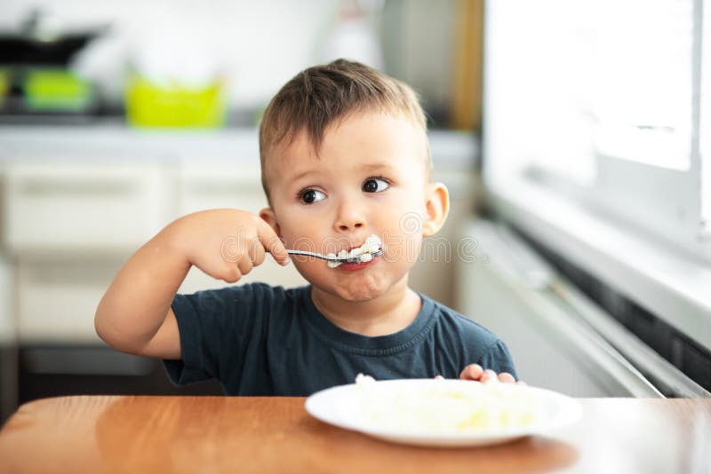 A Little Boy in the Kitchen Greedily Eats Rice with a Spoon Stock Image ...