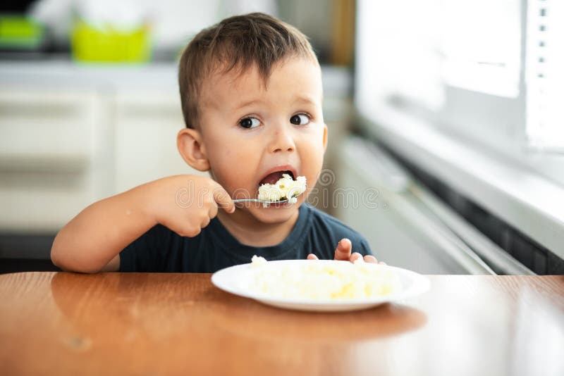 A Little Boy in the Kitchen Greedily Eats Rice with a Spoon Stock Image ...