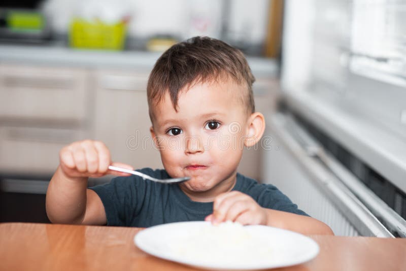 A Little Boy in the Kitchen Greedily Eats Rice with a Spoon Stock Image ...