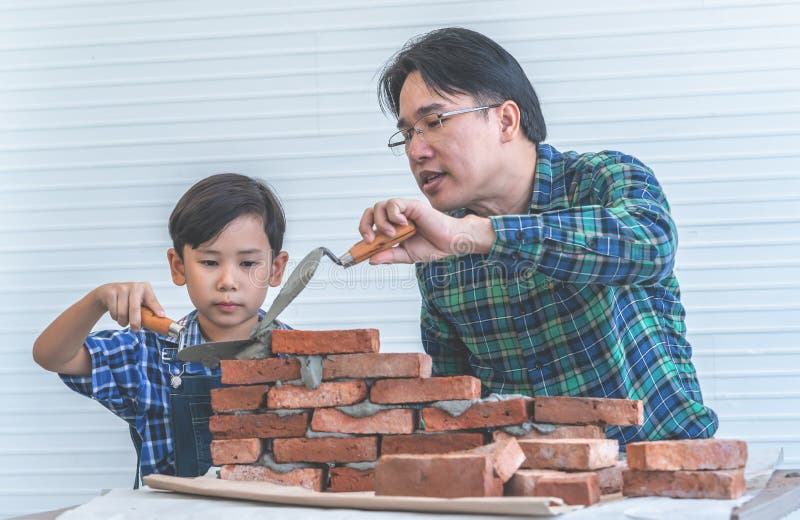 Little Boy Learning How To Lay Down Brick Work from His Builder Father ...