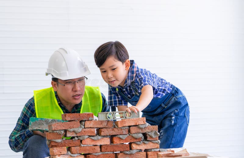 Little Boy Learning How To Lay Down Brick Work from His Builder Father ...