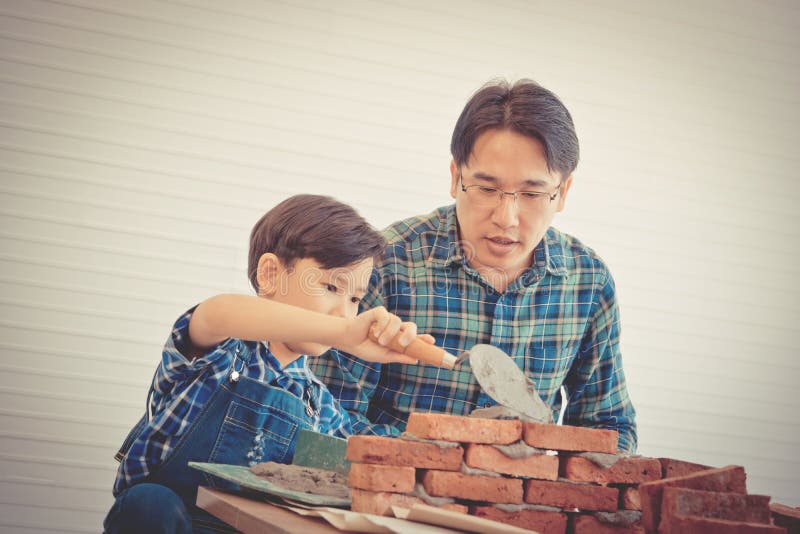 Little Boy Learning How To Lay Down Brick Work from His Builder Father ...