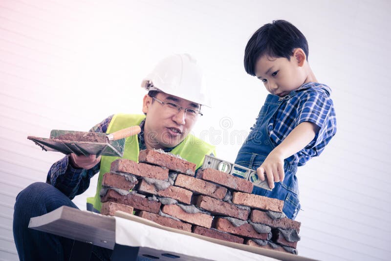 Little Boy Learning How To Lay Down Brick Work from His Builder Father ...
