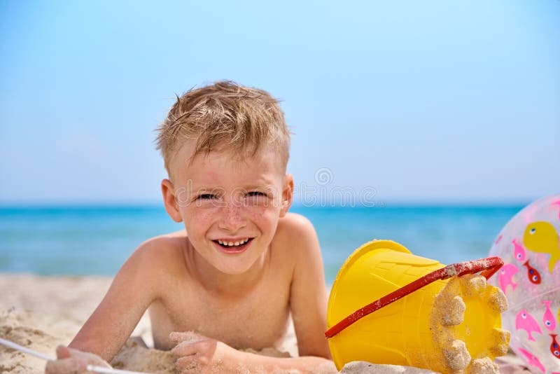 LITTLE BOY LIES on a BLUE SEA SANDY BEACH Stock Image - Image of happy ...