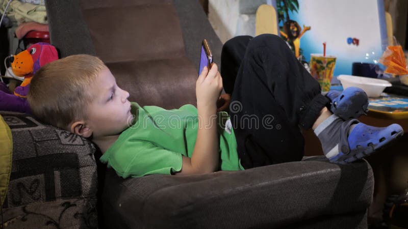 Little Boy Looking at Mobile Phone Screen on Sofa. Gadget Addiction ...