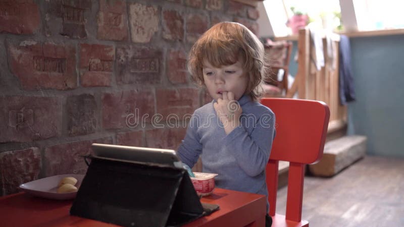 A Little Boy is Looking at the Tablet with Interest Stock Footage ...