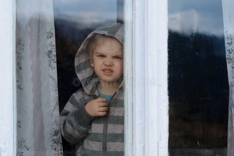 A Small Smeared Boy Looks Worried through a Dirty Window Stock Photo ...