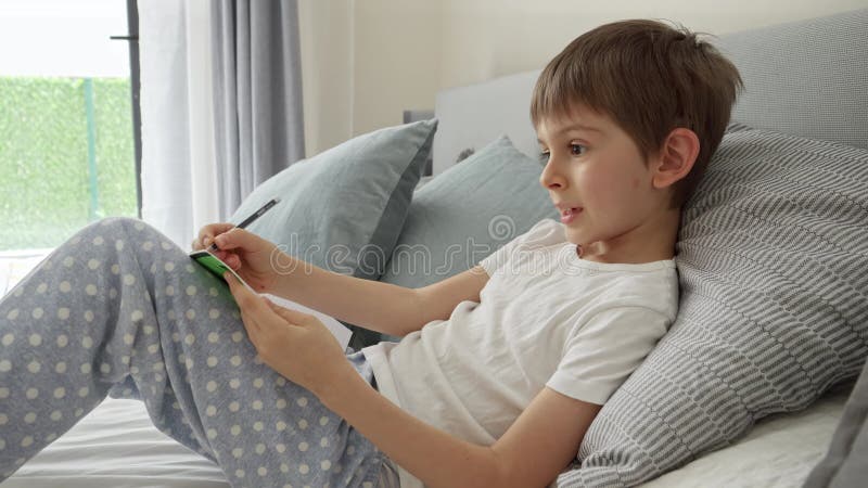 Little Boy Lying in Bed, Writing in Notebook and Ding Homework. Concept ...