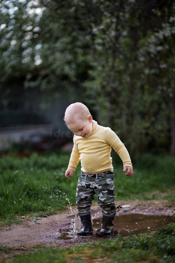 A Little Boy Plaing in the Puddle Stock Photo - Image of nautical ...