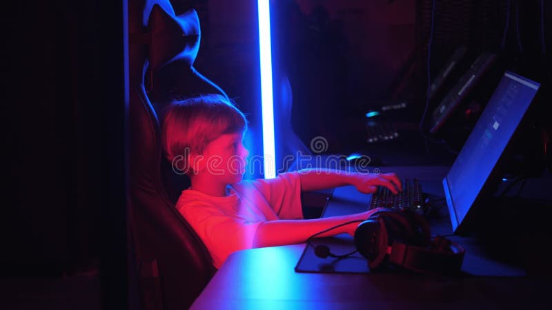 A Little Boy is Playing Computer Games in a Computer Club in the Dark ...