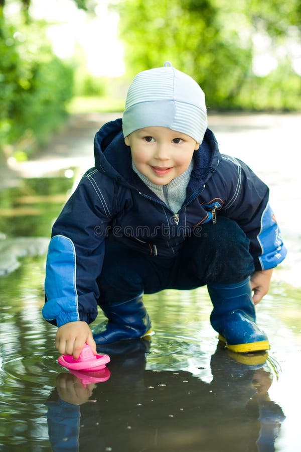 Little Boy Plays in the Puddle Stock Photo - Image of rainboots, coat ...