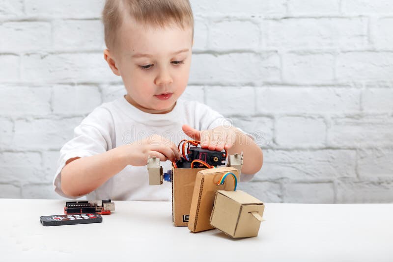 Little Boy Plays with the Robot. Child Collects a Robot Sitting at the ...