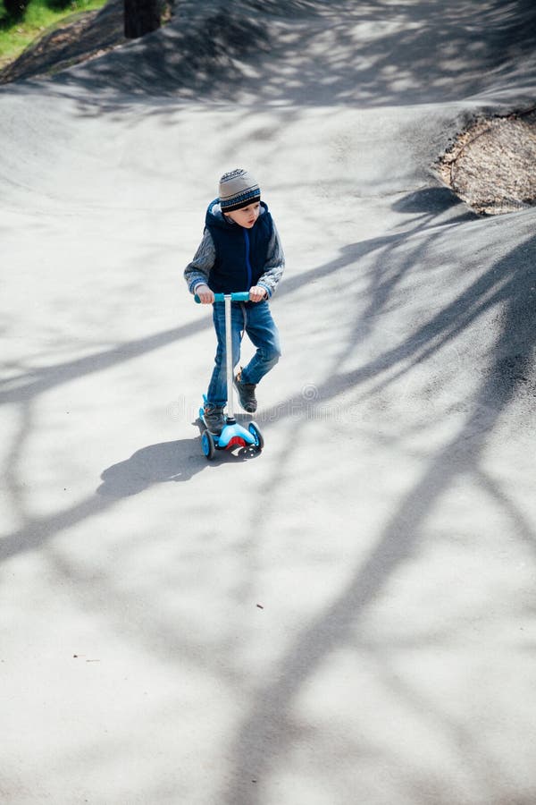 A Little Boy on a Scooter Rides through the Streets of the City Stock ...