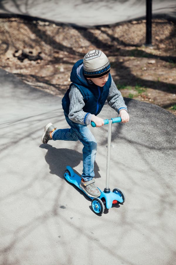 A Little Boy on a Scooter Rides through the Streets of the City Stock ...