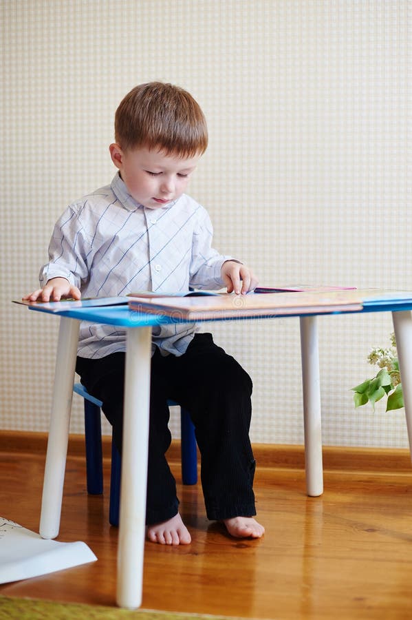 Little Boy Sitting at the Desk and Reading a Book Stock Photo - Image ...
