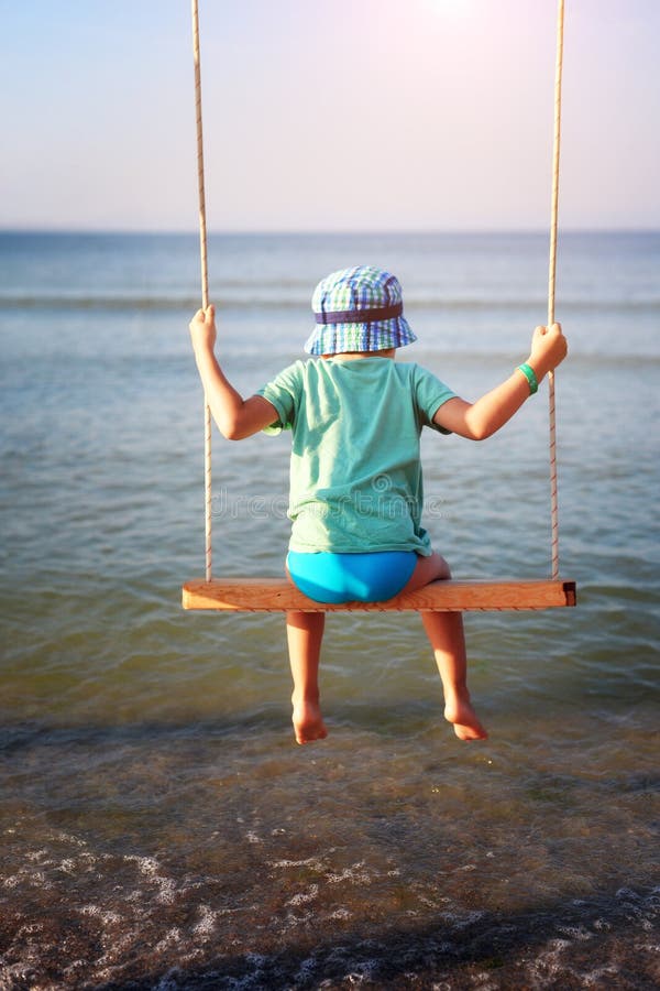 Boy Sitting on a Swing Over the Sea Stock Photo - Image of rope ...